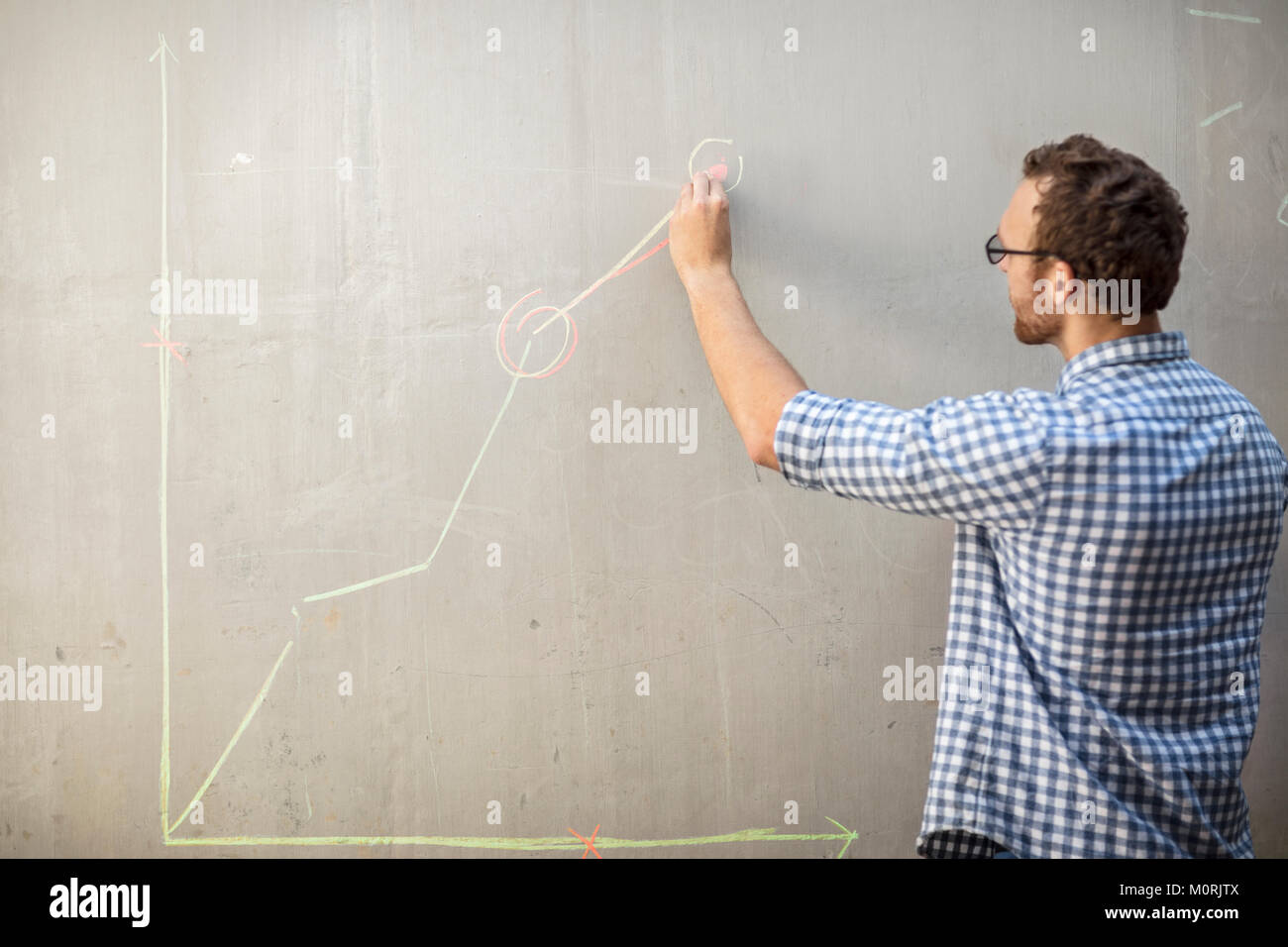 Man drawing a graph with chalk on a concrete wall Stock Photo - Alamy