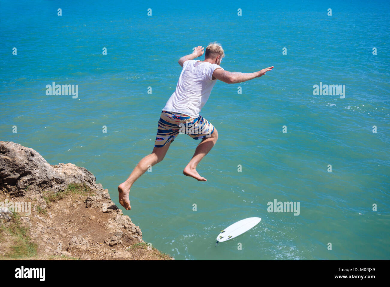 Indonesia, Bali, surfer jumping into water Stock Photo - Alamy