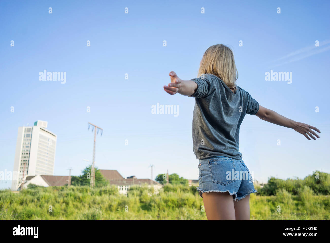 Back view of young woman with arms outstretched Stock Photo - Alamy