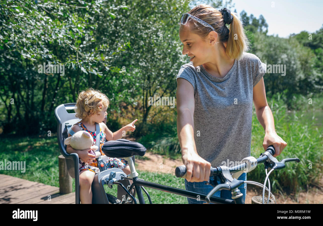Mother taking a bike ride through the countryside with her daughter in ...