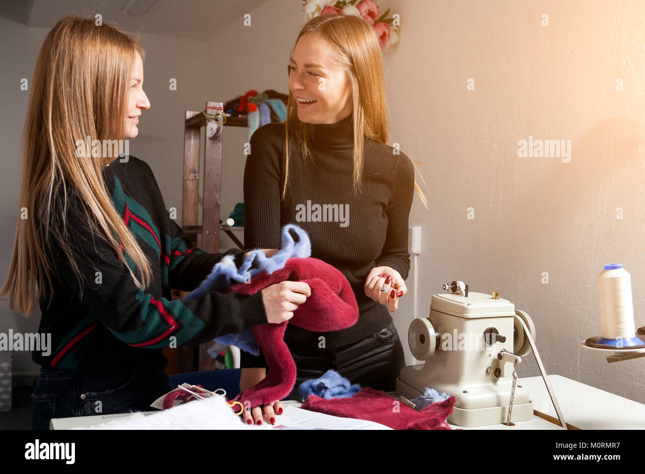 Two young women furriers smiles and advise how to properly sew a fur ...