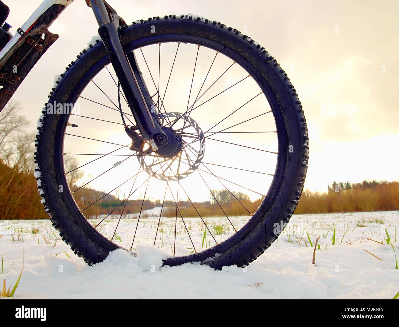 Front wheel of mountain bike stay in snow. Snow flakes melting on dark ...