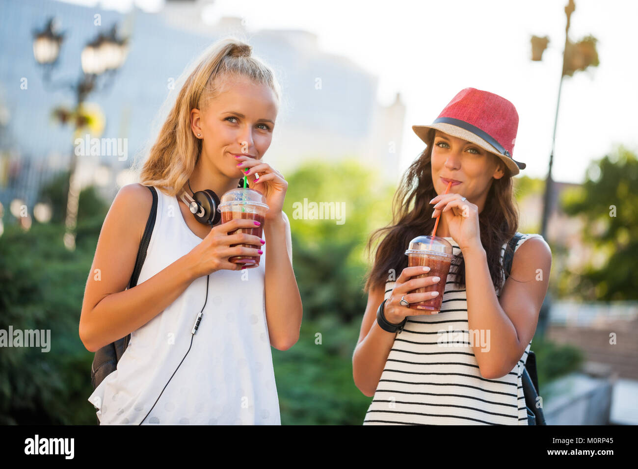 Two happy women are having nice time together in the city. They are ...
