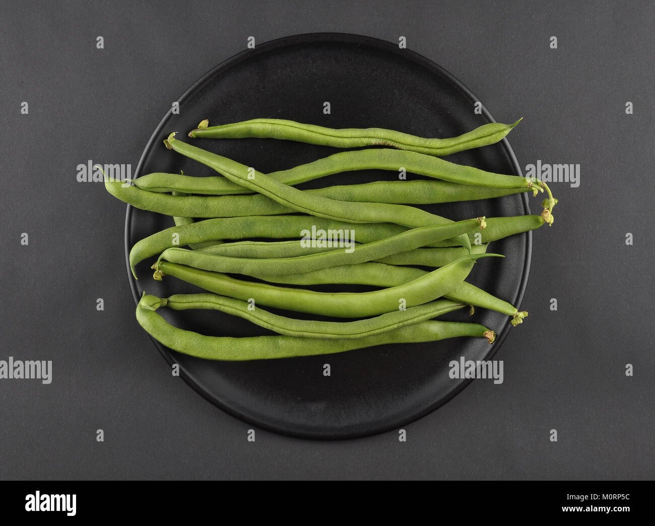 Beans on plate and black background Stock Photo - Alamy