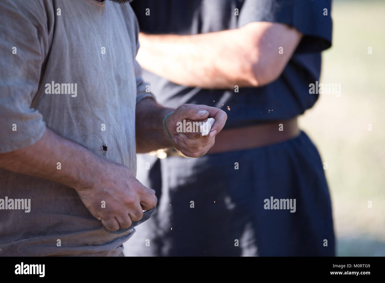 Man who creates sparks using a flint and an iron object Stock Photo - Alamy