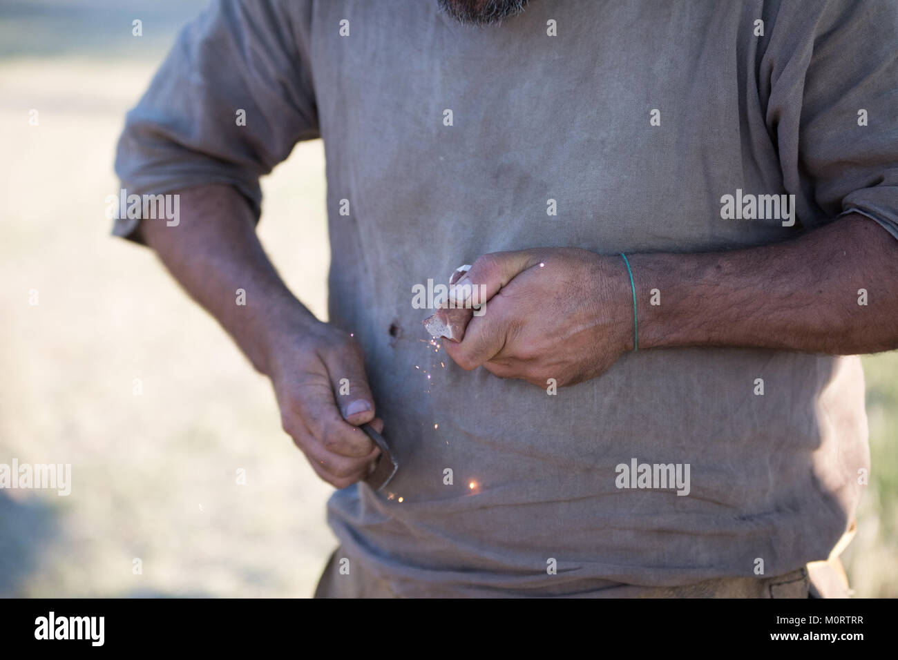 Man who creates sparks using a flint and an iron object Stock Photo - Alamy