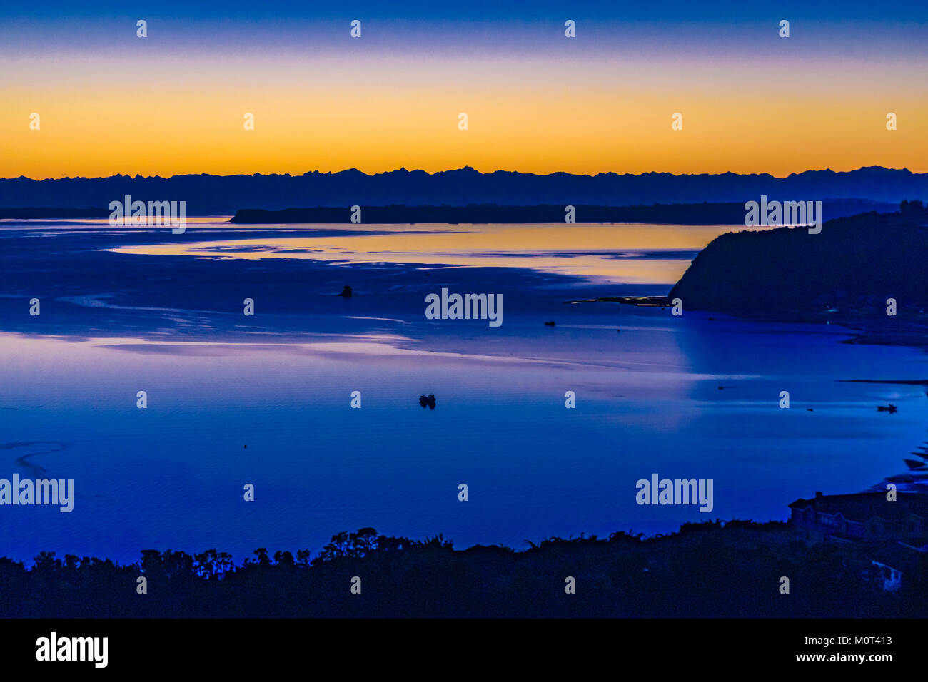 Sunset landscape scene with fjord and mountains as main subject, Chiloe ...