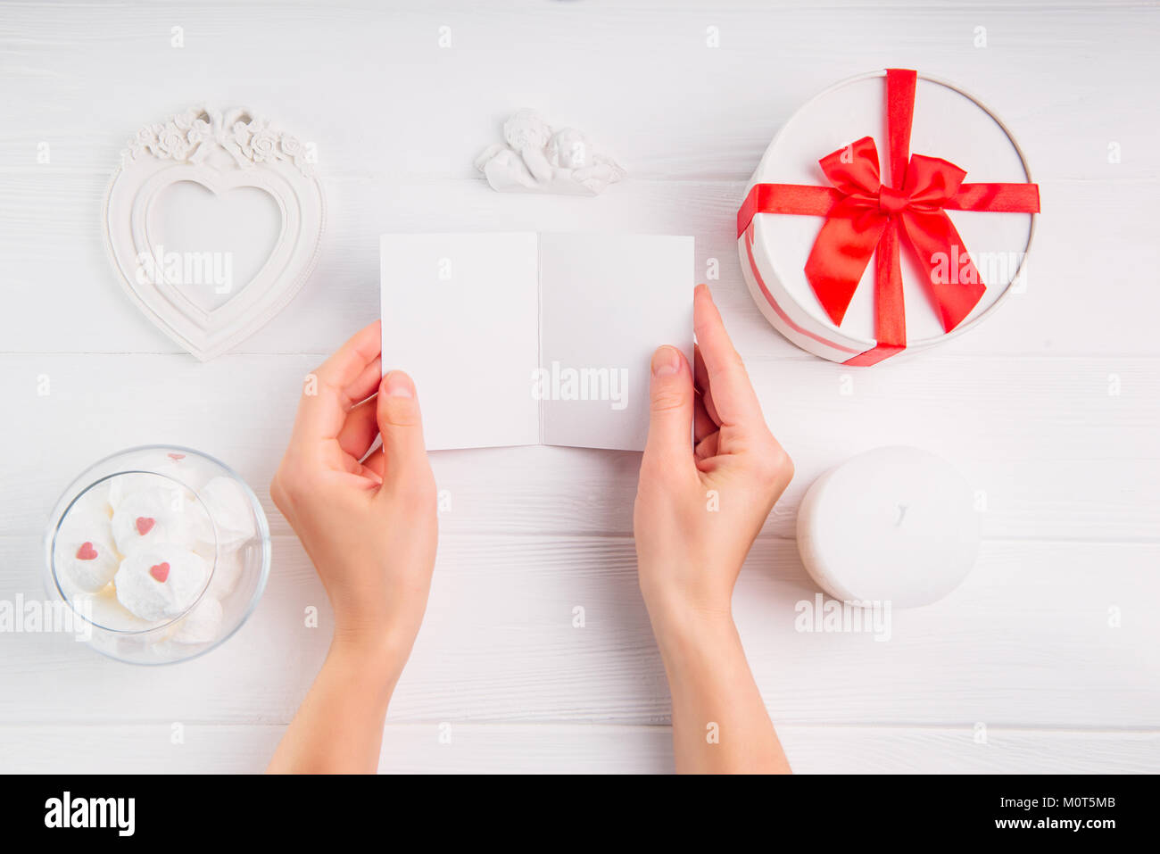 Women's hands holding empty greeting card on white background with ...