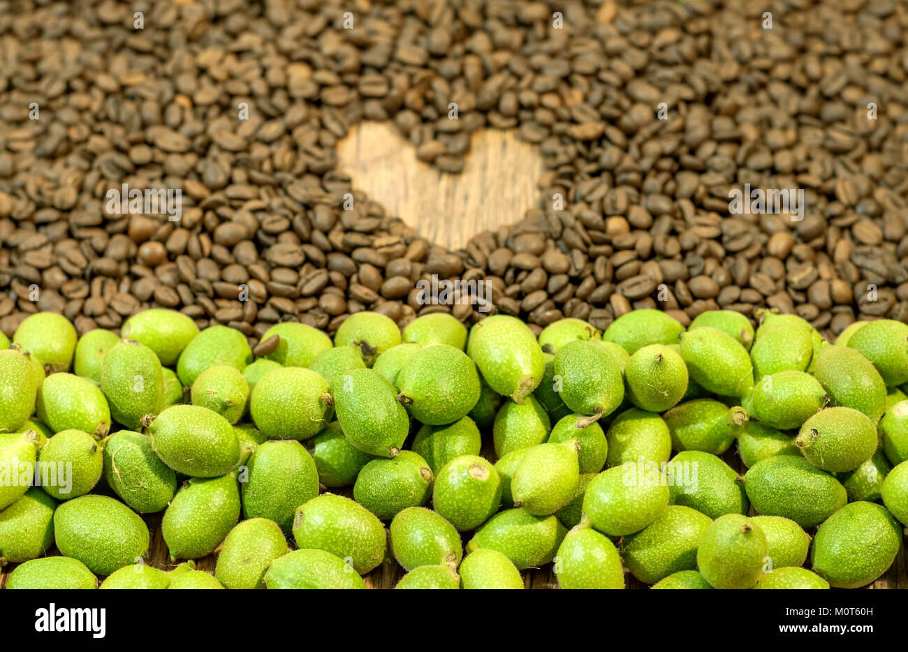 Green young walnuts in husks in front and in the back coffee benas with ...