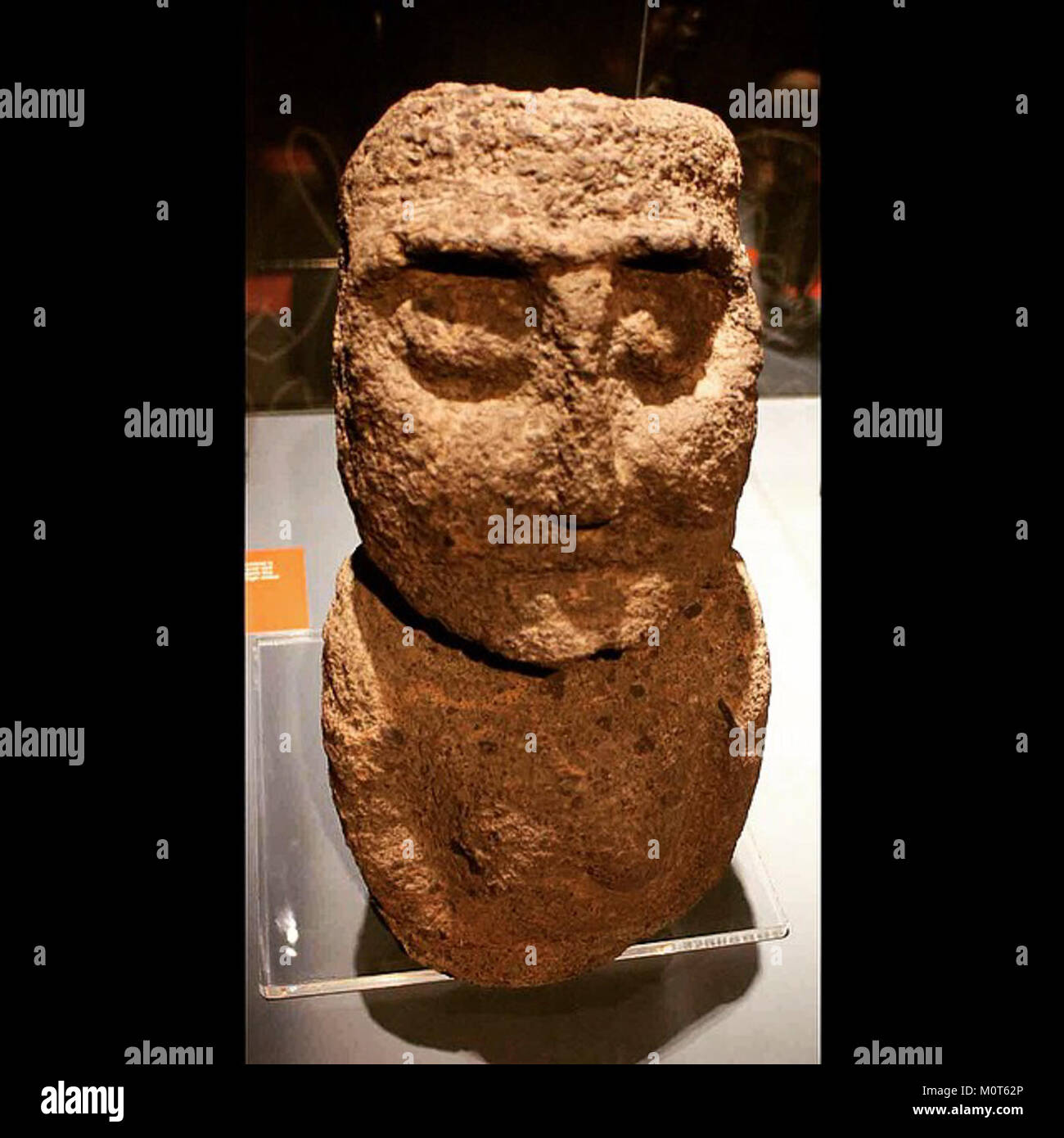 A carved stone sculpture depicting a head and body. This piece is ...