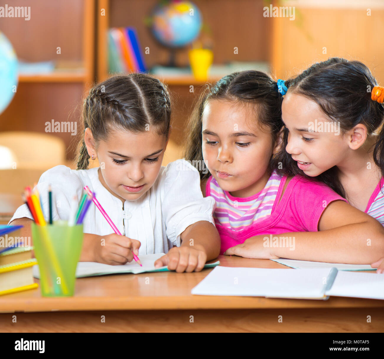 Happy elementary students in classroom at school Stock Photo - Alamy