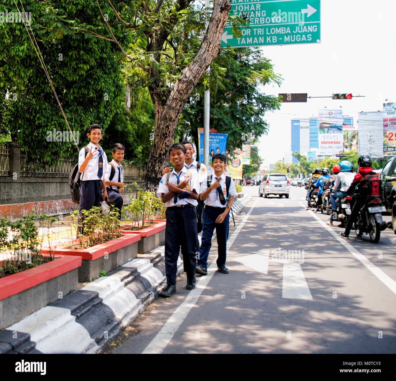 Javanese school boys laugh and smile as they walk along the busy street ...