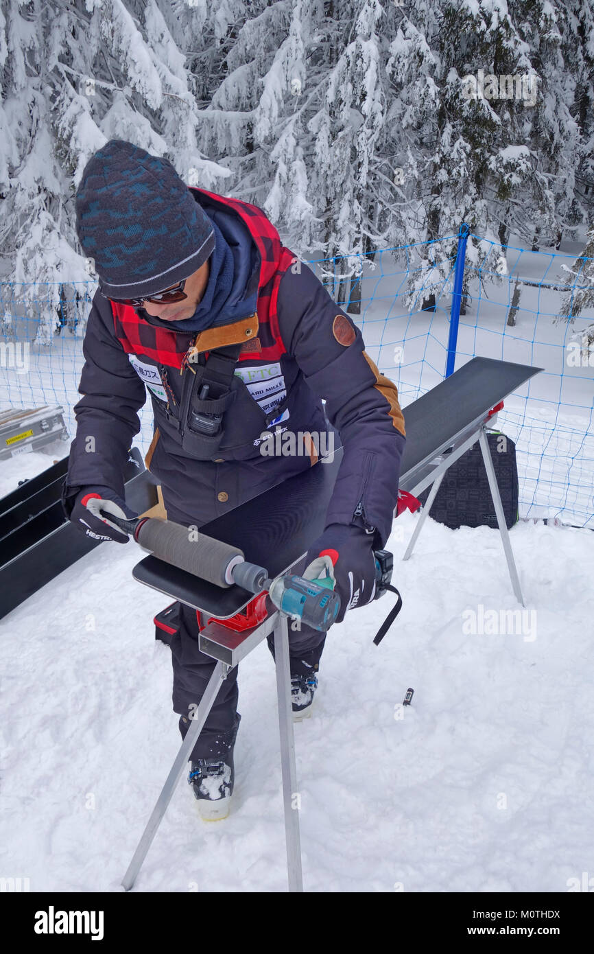 Ski board servicer polishes a board behind start line during ...