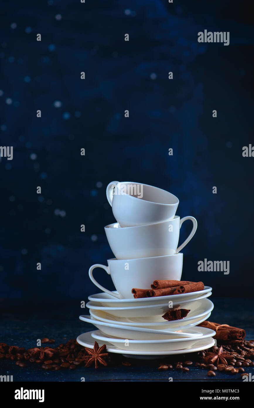 Stack of balancing white coffee cups and tea saucers with coffee beans ...