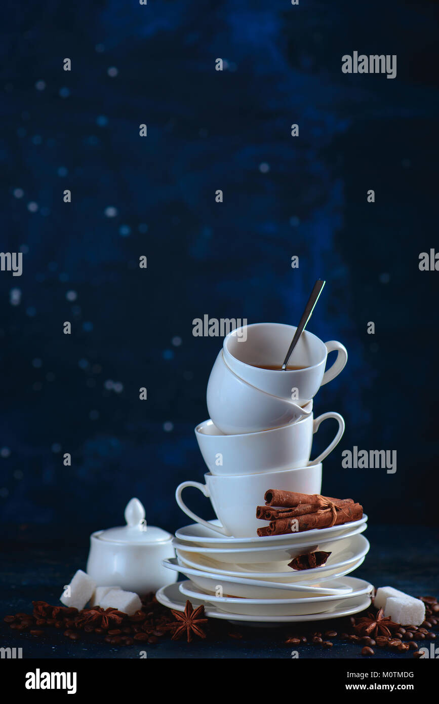 Stack of balancing white coffee cups and tea saucers with coffee beans ...
