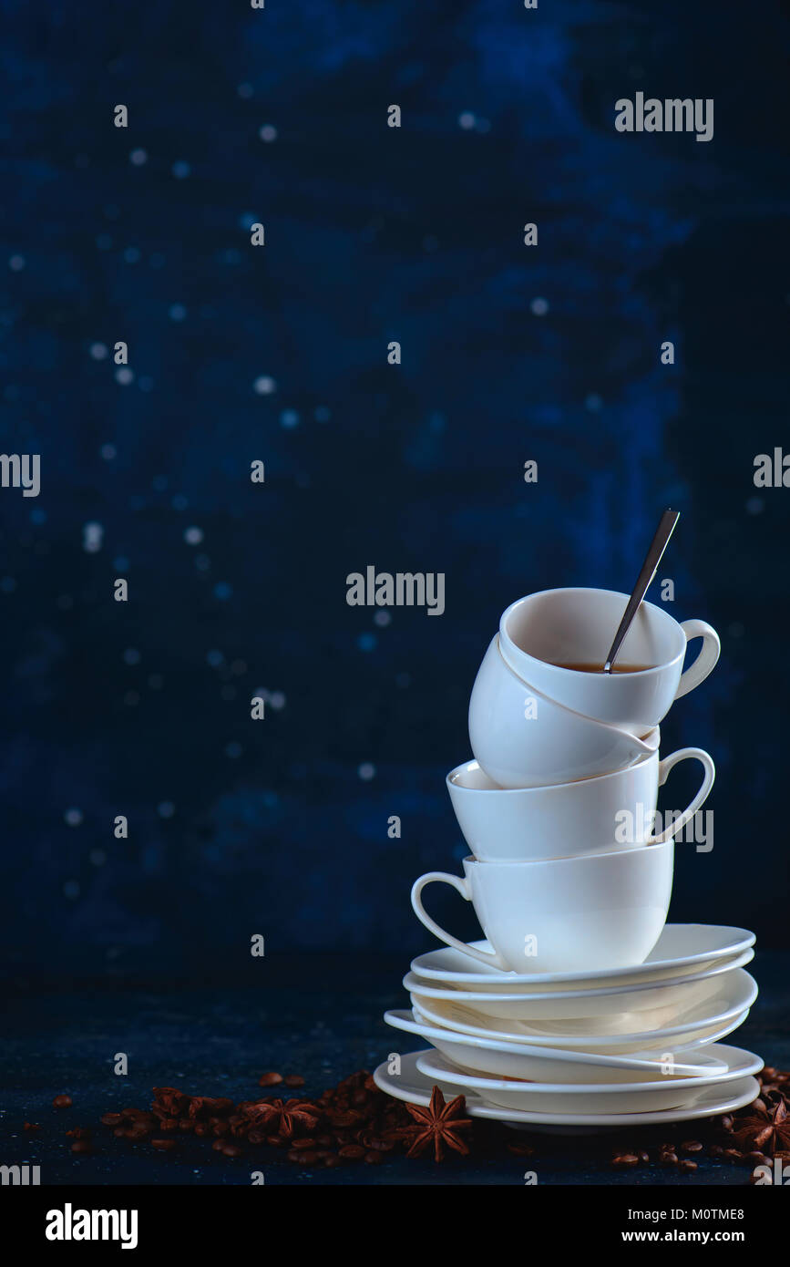 Stack of balancing white coffee cups and tea saucers with coffee beans ...