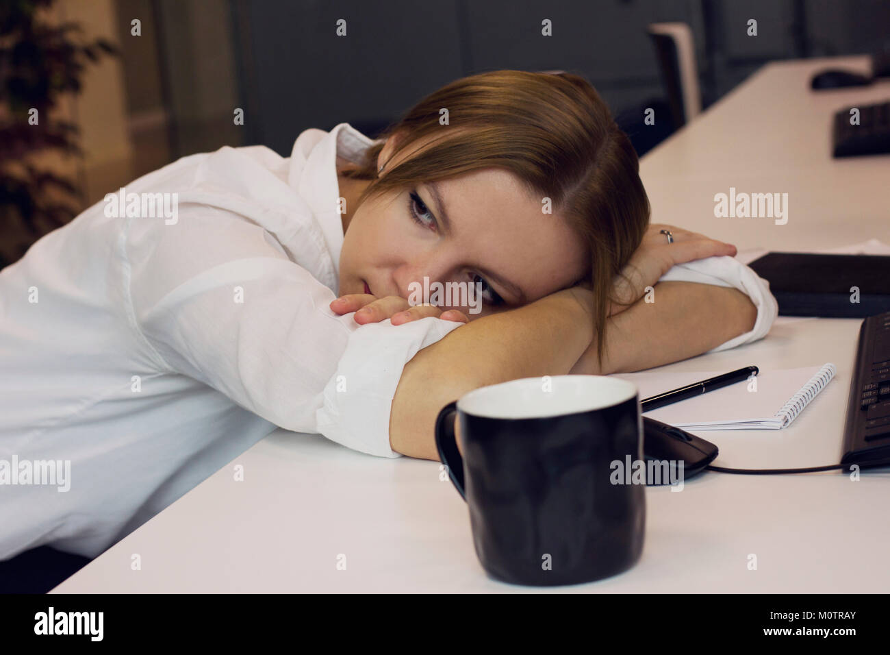 Tired young woman laid her head down on the Desk in the office Stock ...