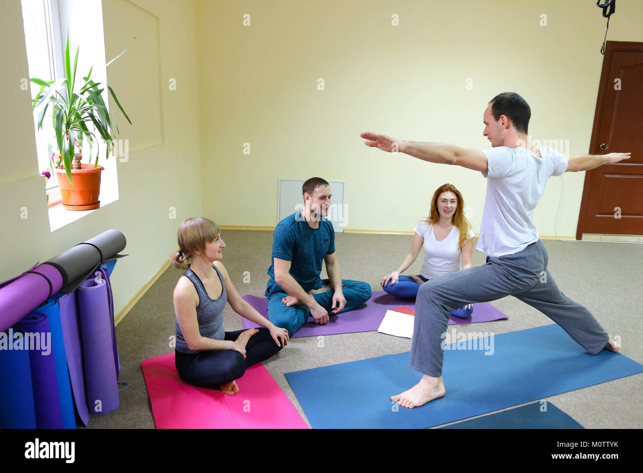 Four young people sit on floor on yoga mats and communicate Stock Photo ...