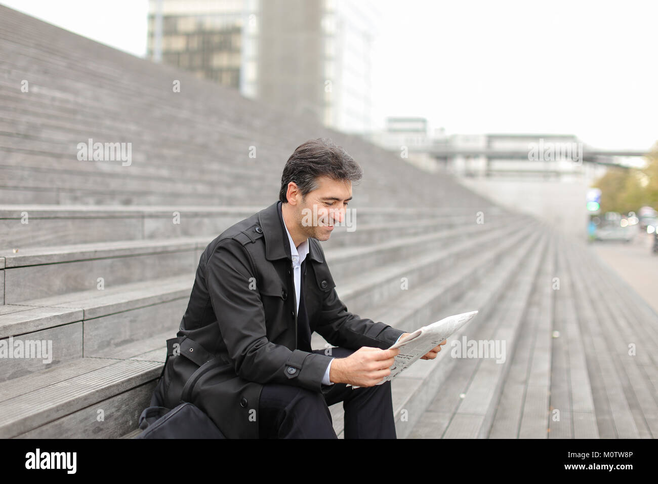 male business tutor sitting on stairs and reading newspaper Stock Photo ...