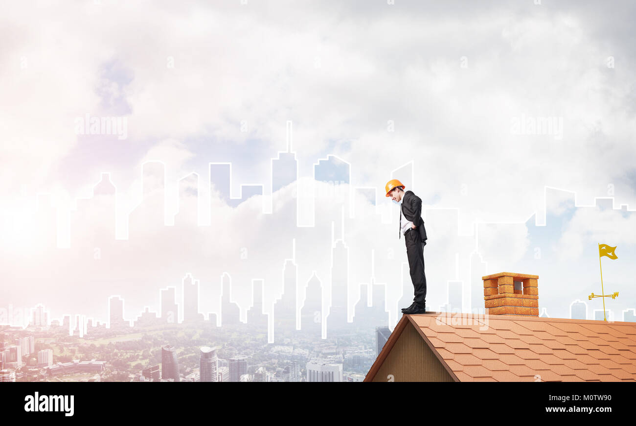 Engineer man standing on roof and looking down. Mixed media Stock Photo ...