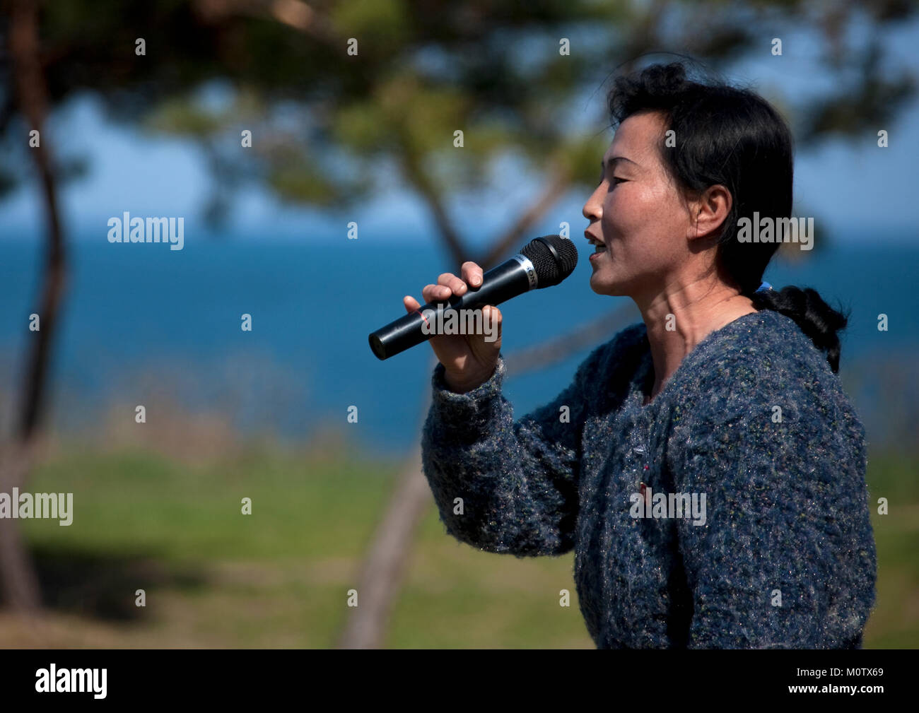 North Korean woman singing with a mircophone during a pioneers camp ...