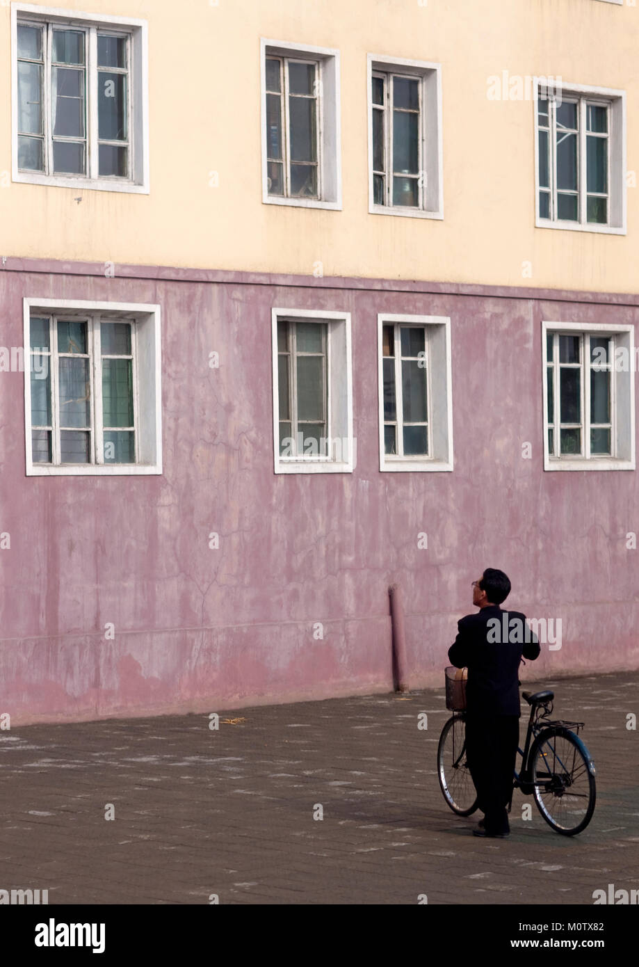 North Korean man with a bicycle speaking to someone in a building ...