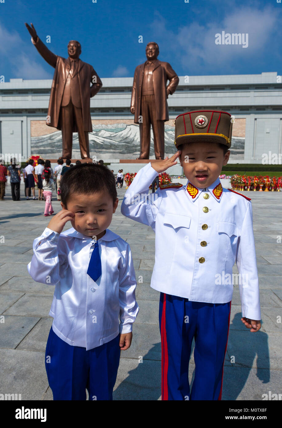 North Korean children saluting like soldiers in front of the statues of ...