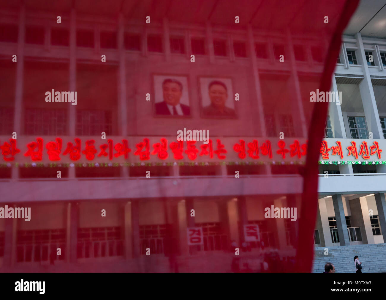 Red flag in front of the official portraits of the Dear Leaders on a ...