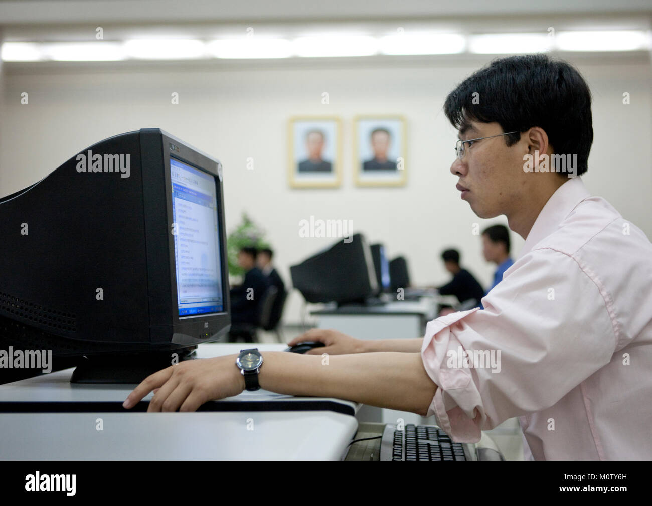 North Korean man using a computer under the Dear Leaders pictures in ...