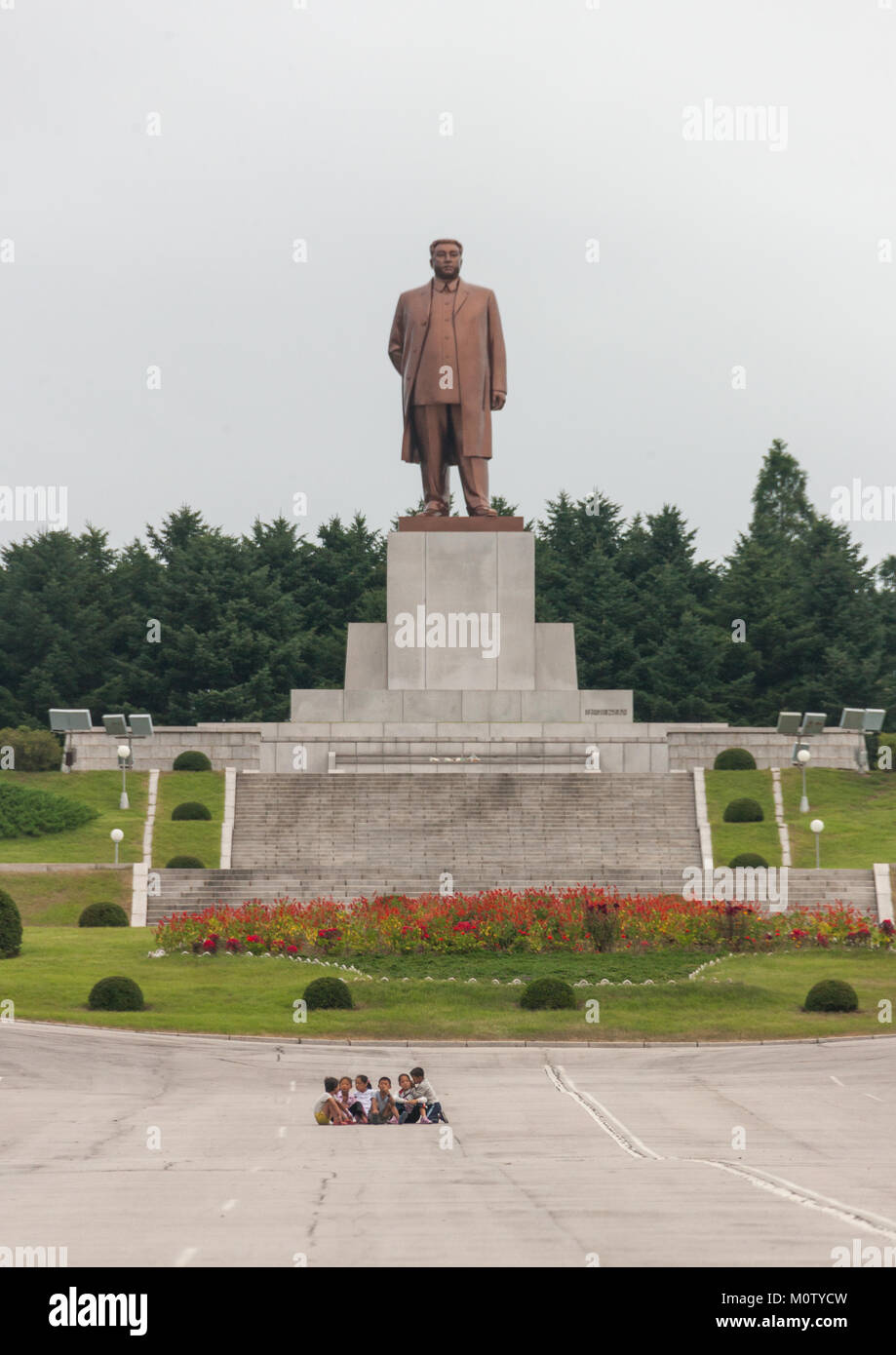 North Korean children sit in front of Dear leader Kim il Sung statue ...