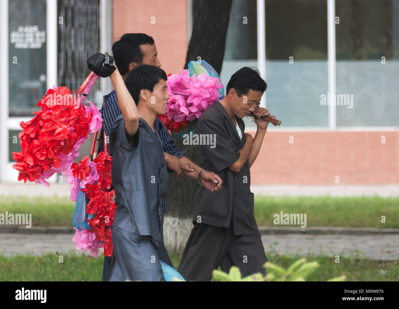 North Korean men with plastic flowers going celebrate the day of the ...
