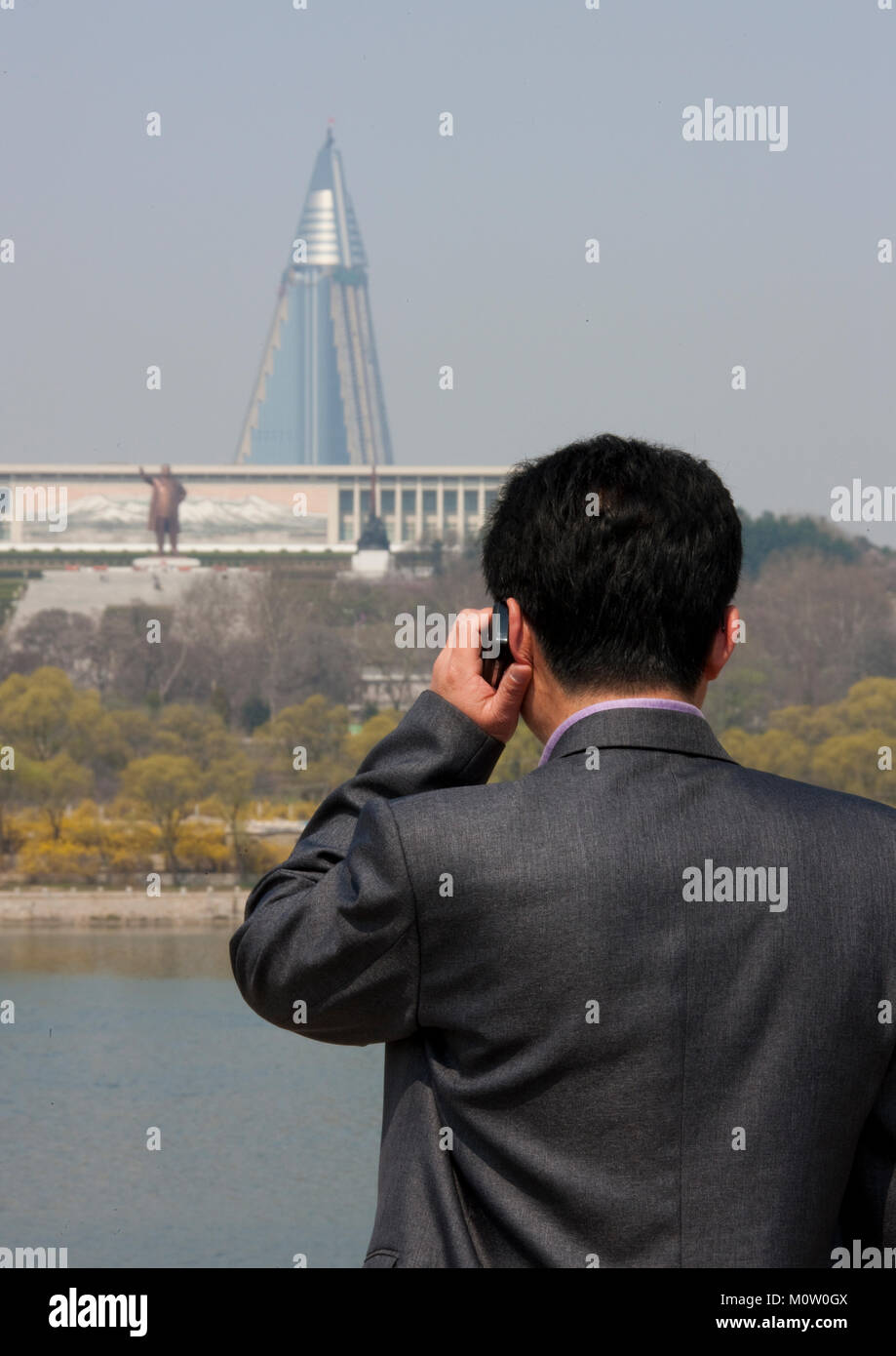 North Korean man calling with his mobile in front of the pyramid-shaped ...