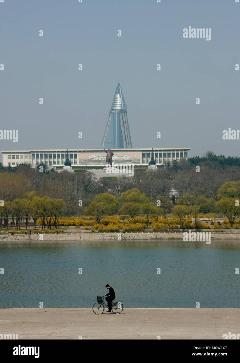 Man on a bike with Ryugyong hotel and Mansudae Grand monument in the ...