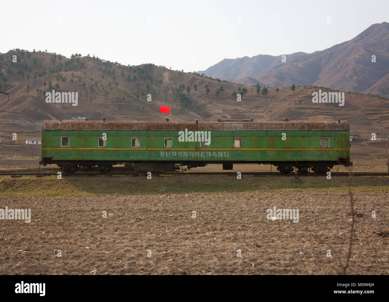 North Korean rusty train with a red flag stopped in the countryside ...