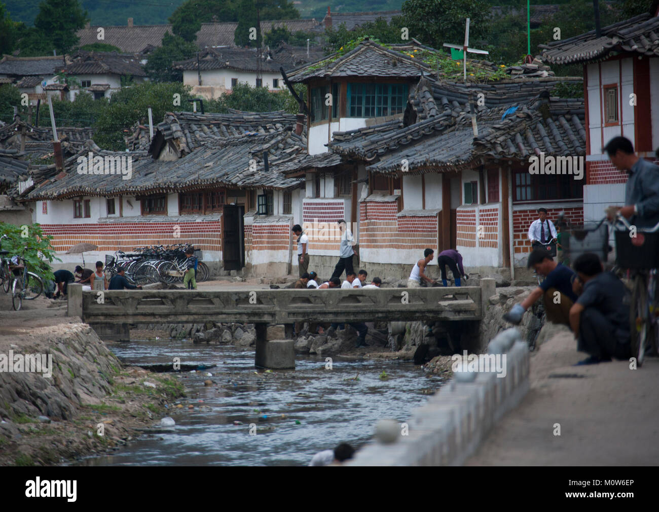 North Korean people crossing bridge over a little river in the old town ...