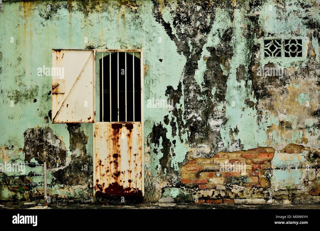 Weathered back of a shop house with rusty iron bi fold door and ...
