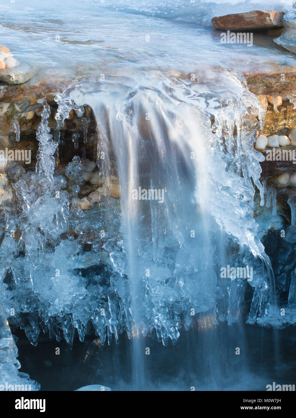 Waterfall covered in ice with water flowing from beneath Stock Photo ...