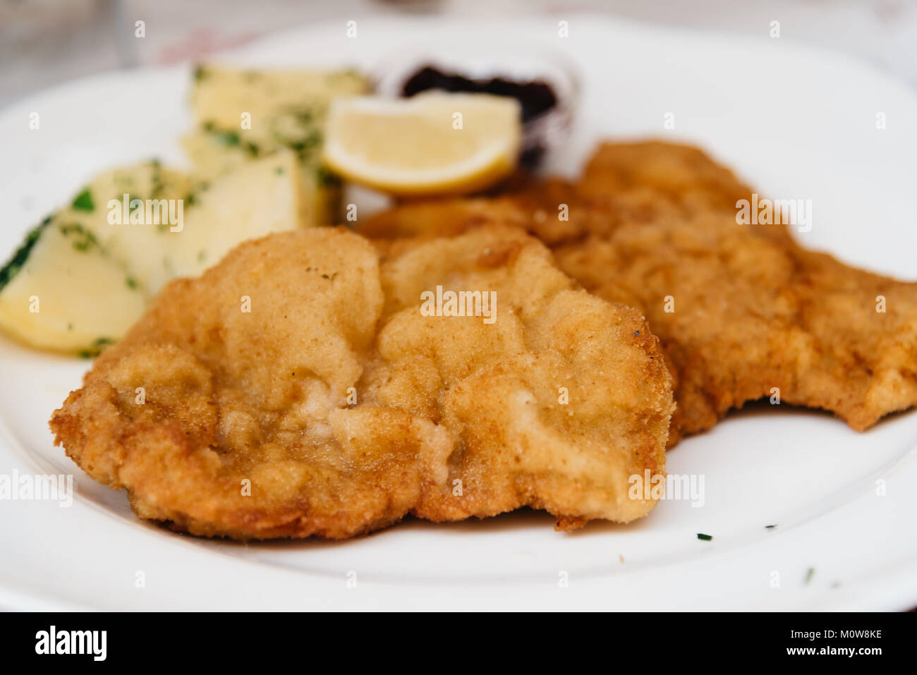 Close up of Wiener schnitzel on white plate in restaurant, side view ...