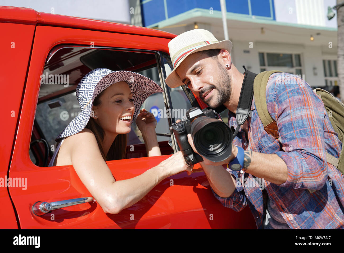 Photographer taking pictures of model sitting in old fashioned pick-up ...
