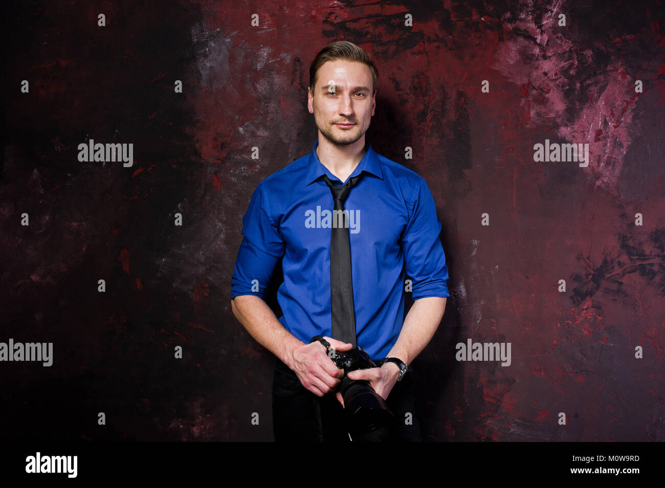Studio portrait of stylish professional photographer man with camera ...