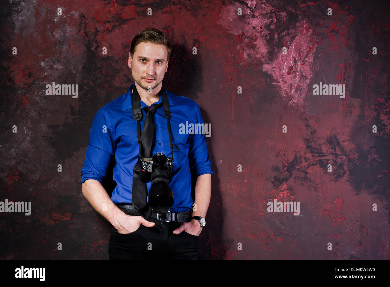 Studio portrait of stylish professional photographer man with camera ...