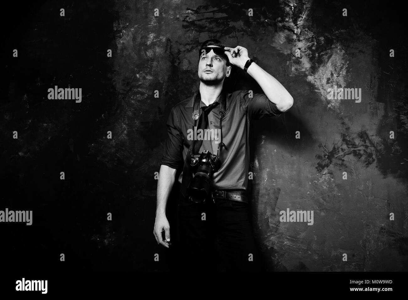 Studio portrait of stylish professional photographer man with camera ...