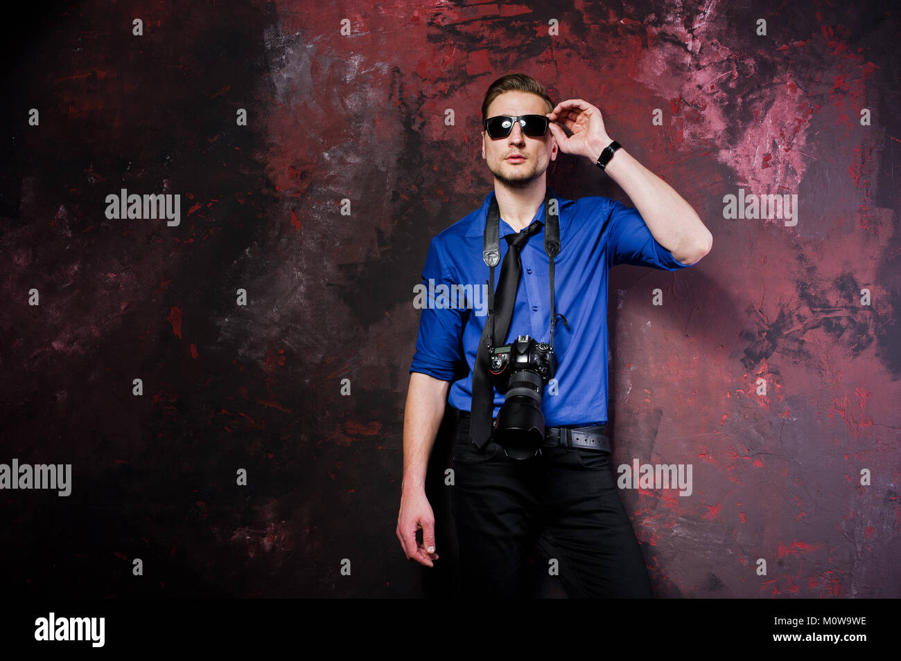 Studio portrait of stylish professional photographer man with camera ...