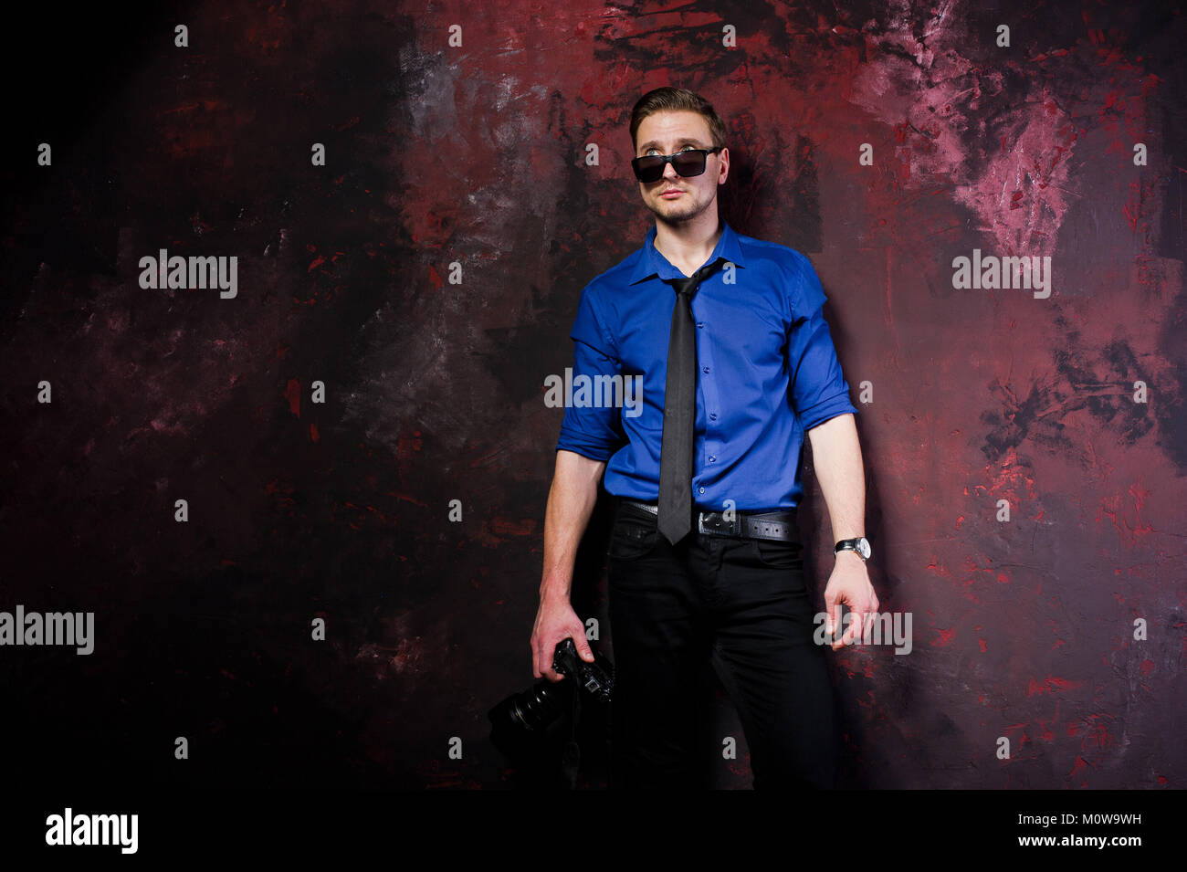 Studio portrait of stylish professional photographer man with camera ...