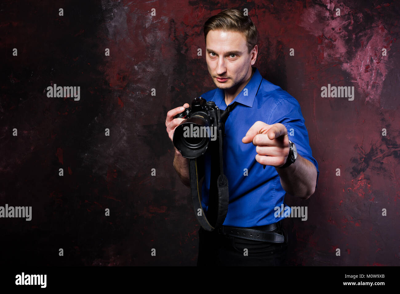 Studio portrait of stylish professional photographer man with camera ...