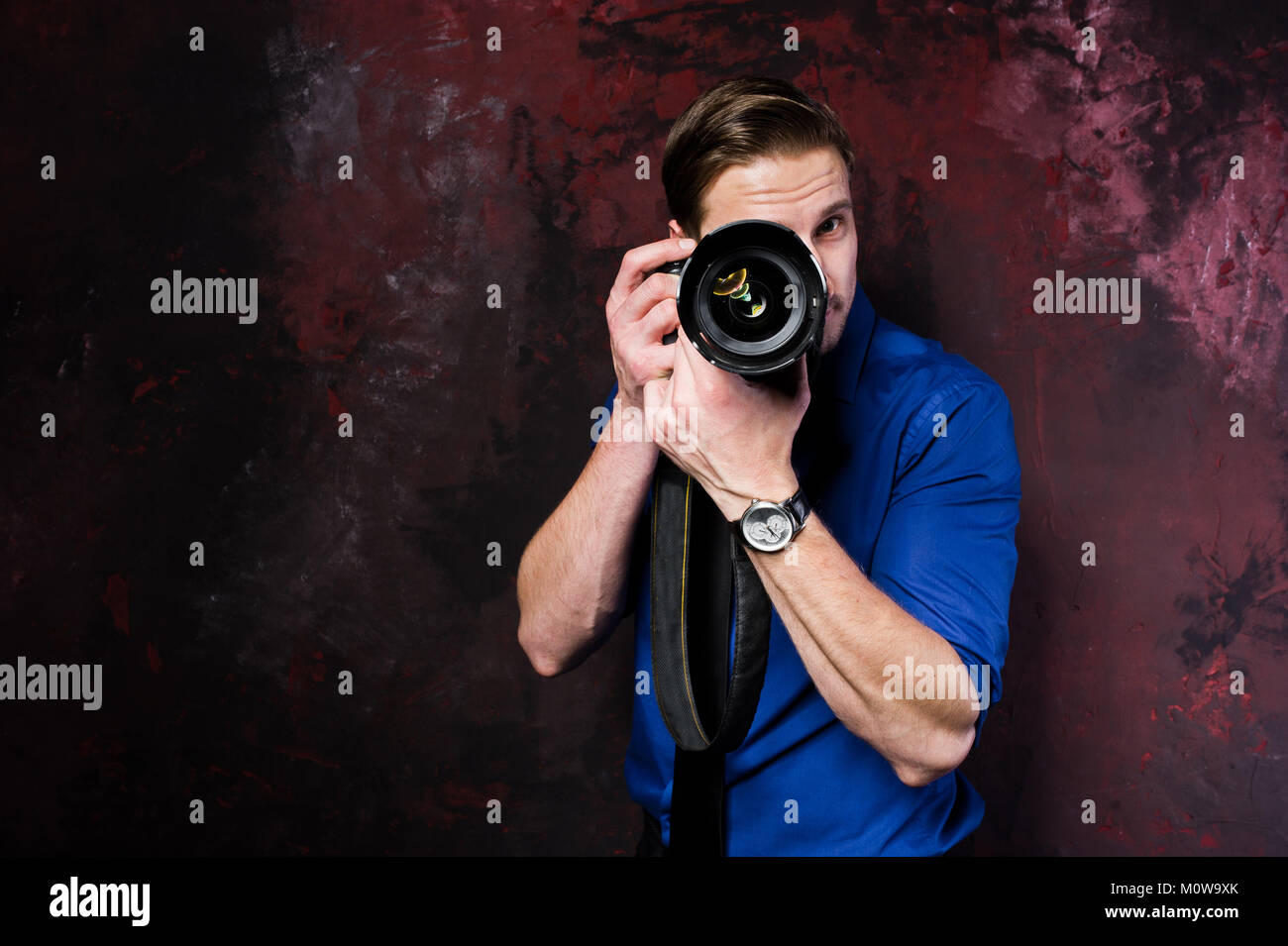 Studio portrait of stylish professional photographer man with camera ...