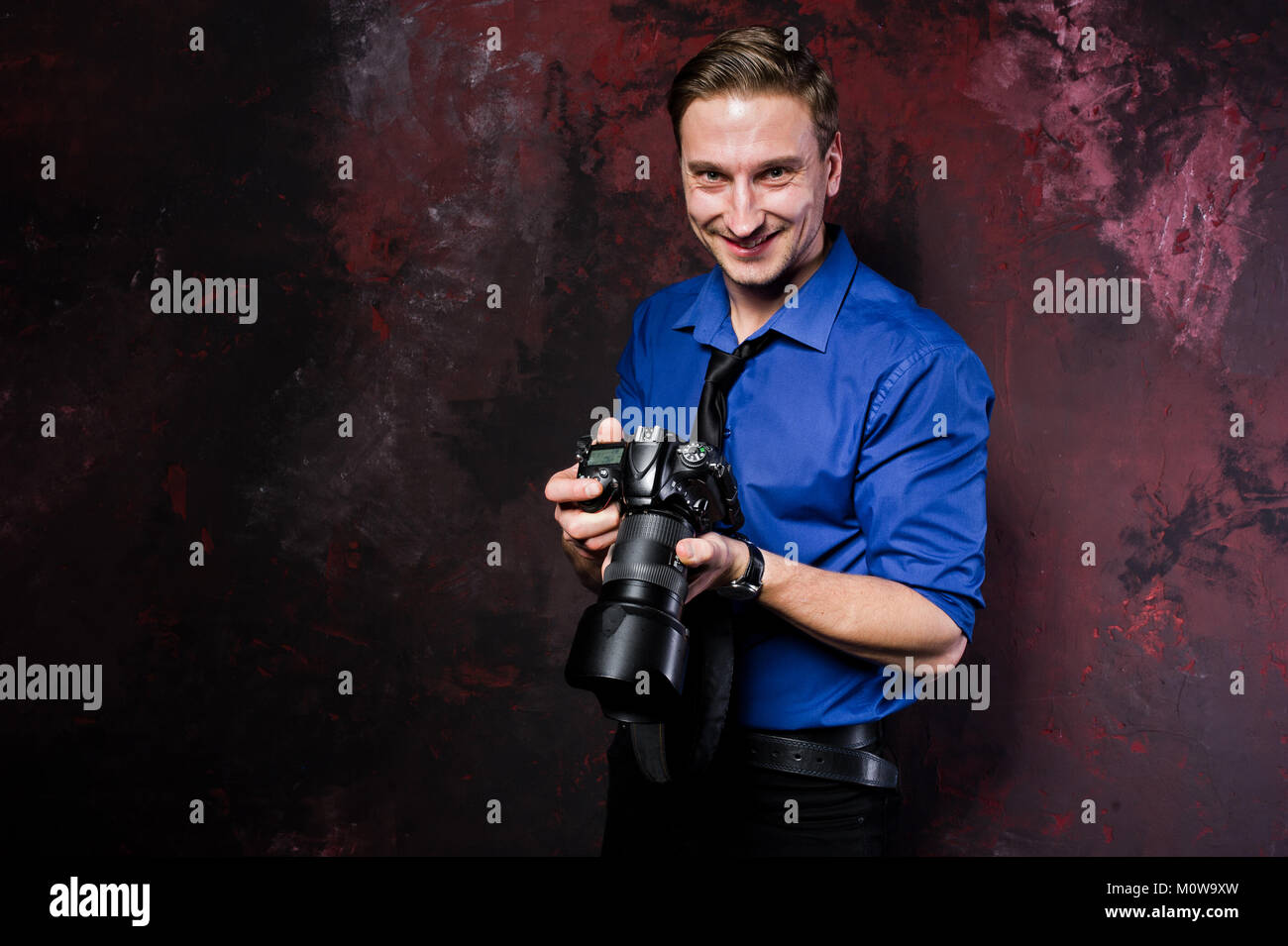Studio portrait of stylish professional photographer man with camera ...