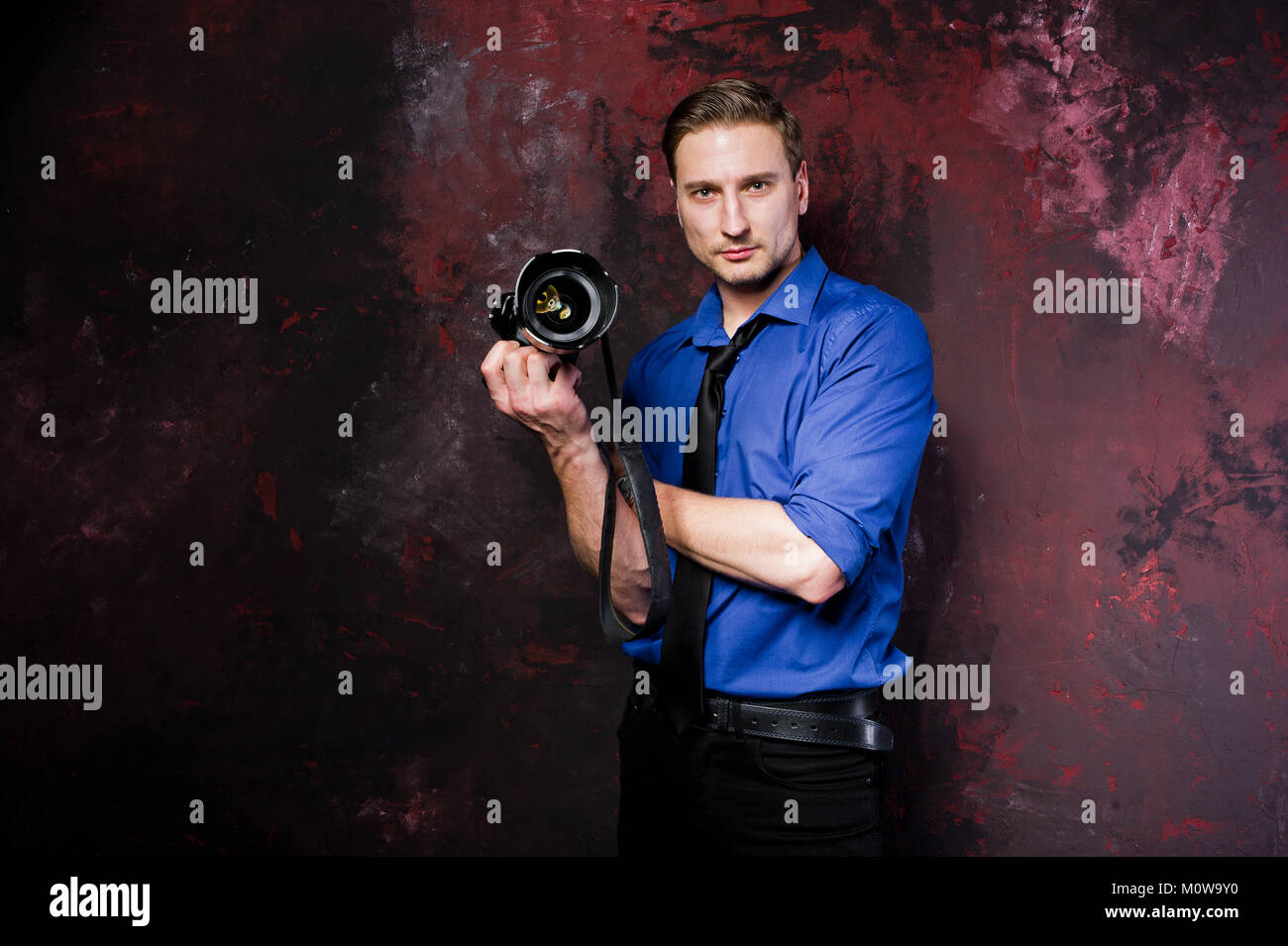 Studio portrait of stylish professional photographer man with camera ...