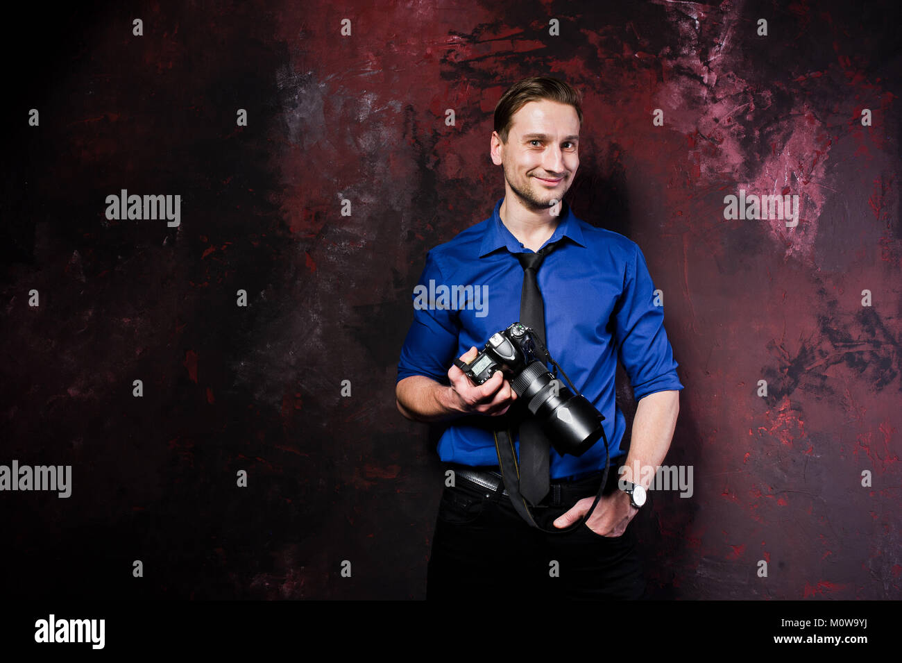 Studio portrait of stylish professional photographer man with camera ...