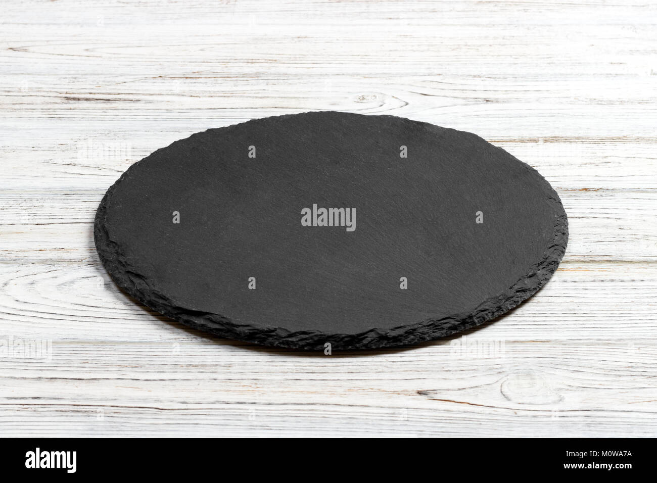 Round natural slate board. Dark gray slate stand on wooden background ...